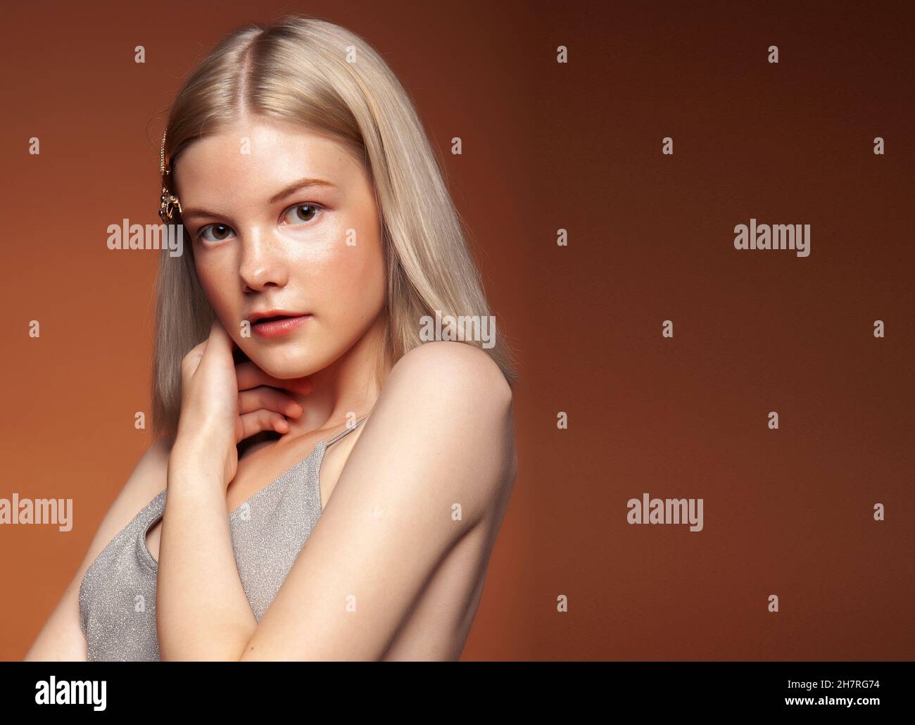 young pretty girl with blond hair posing cheerful on brown background, lifestyle people concept ...