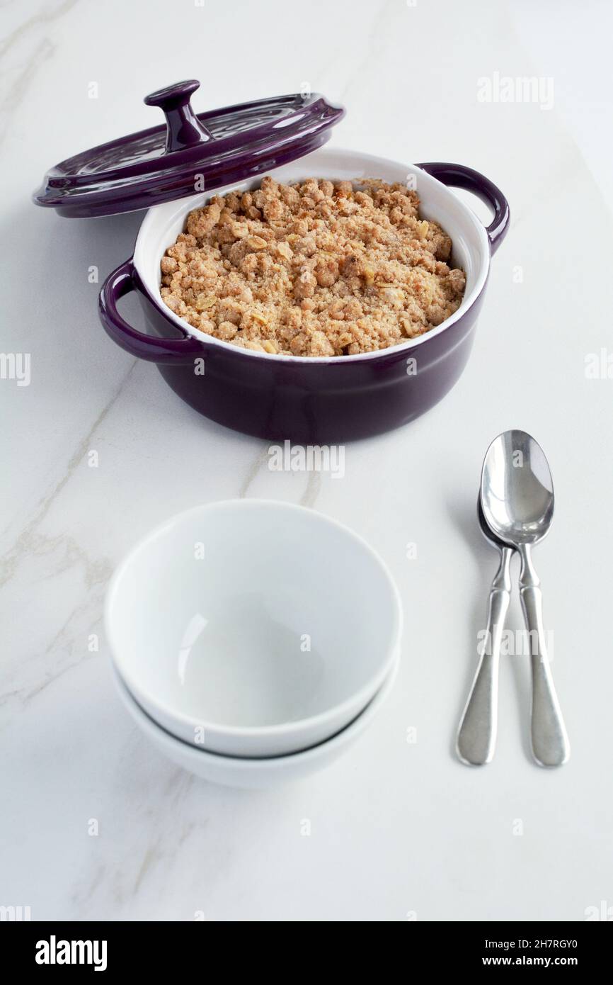 Fresh baked apple crumble in small casserole dish on marble background ...