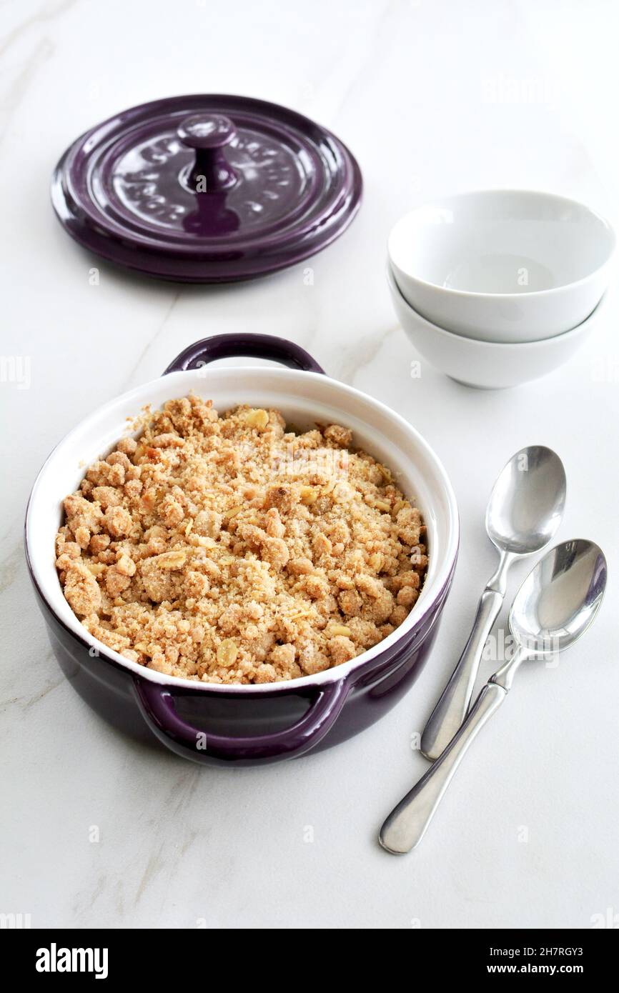 Fresh baked apple crumble in small casserole dish on marble background ...