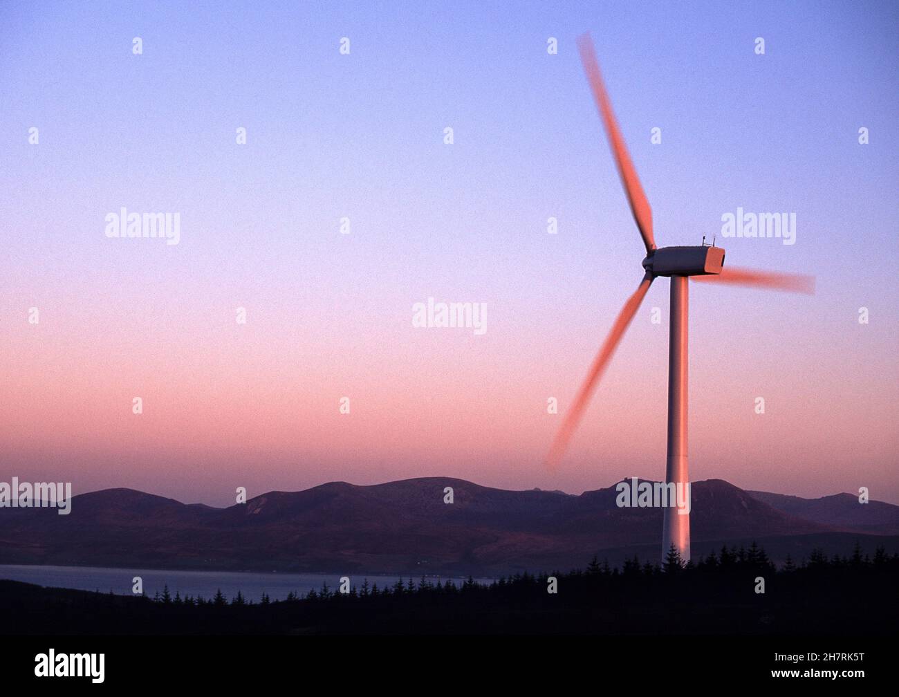 Single wind turbine and blurred moving blades turned pink by the ...