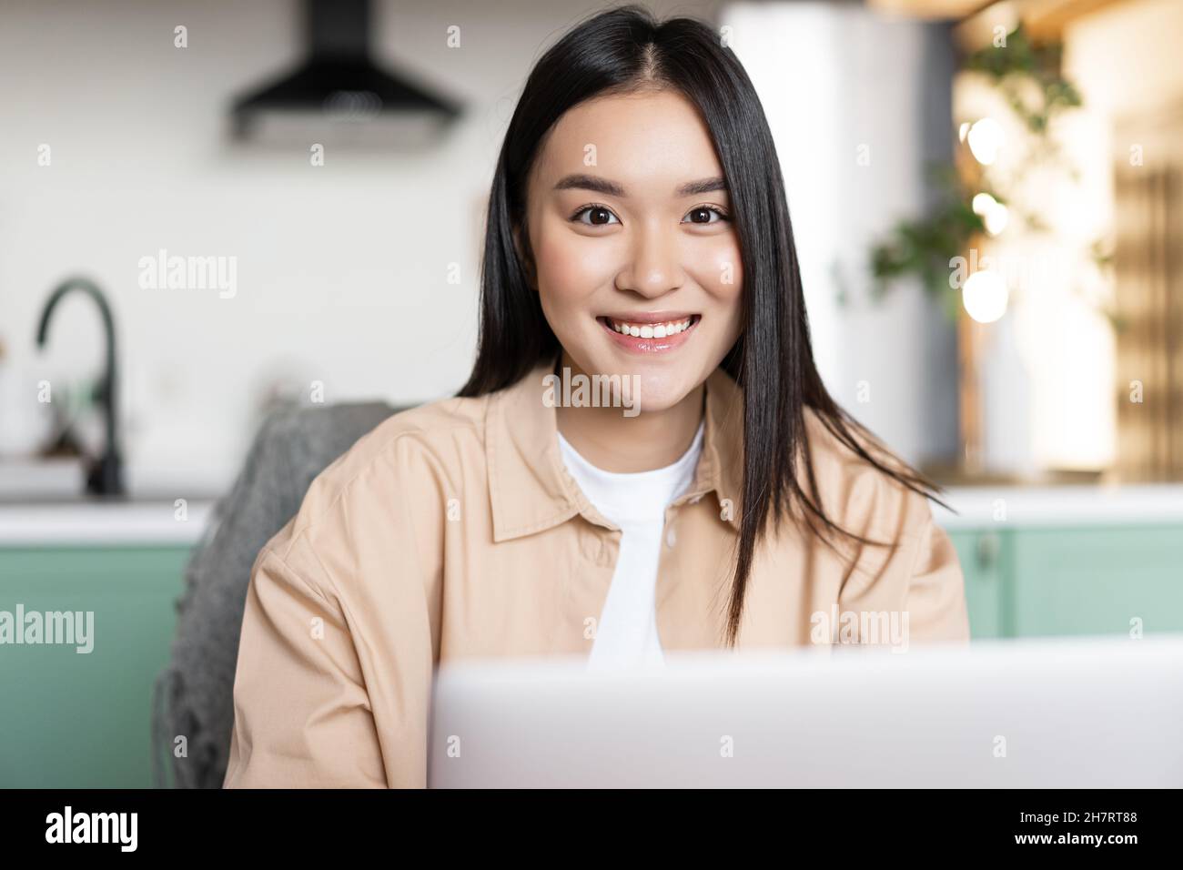 Freelance asian girl sitting at home and working with laptop, smiling ...
