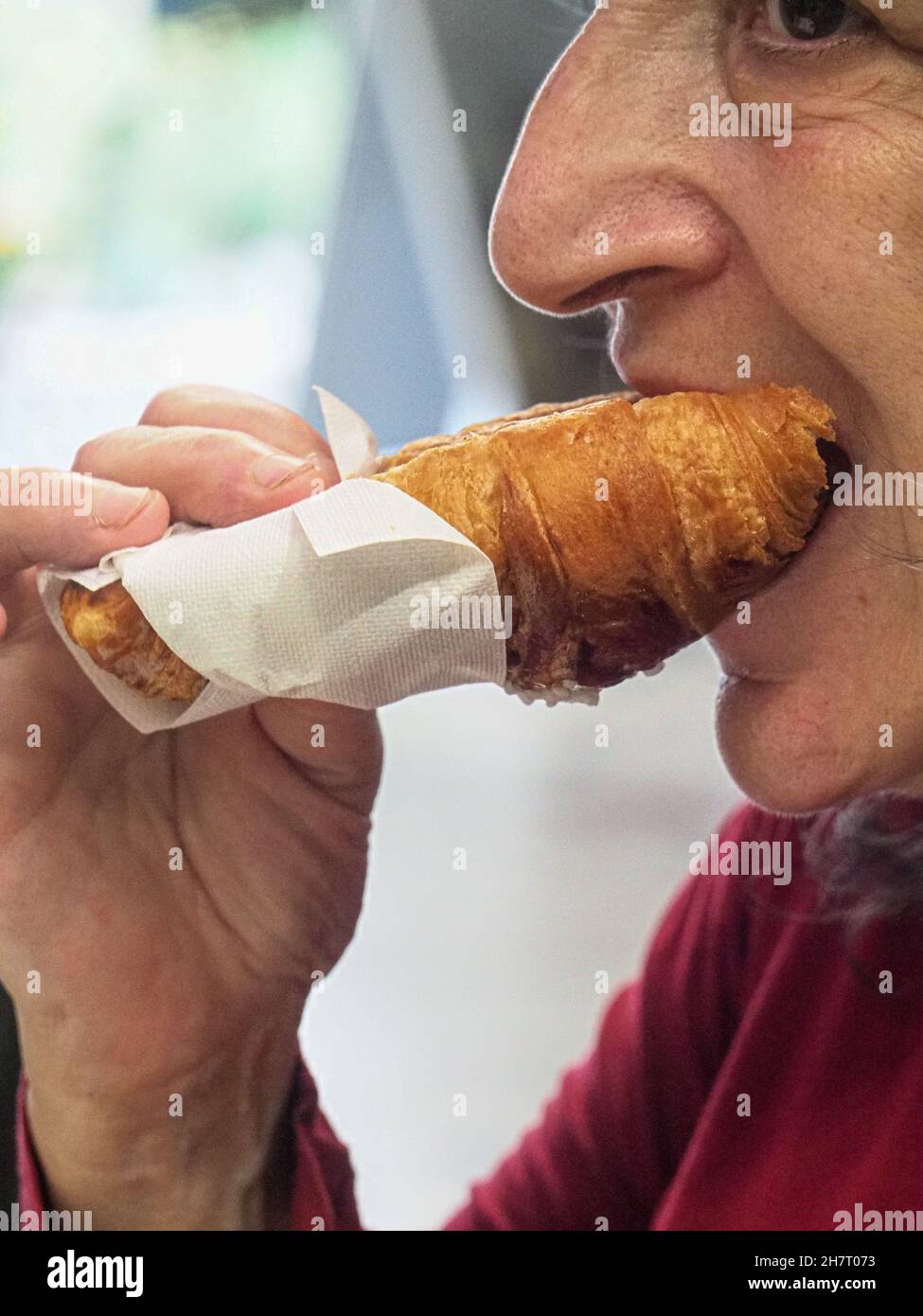 Old Hispanic woman eating a croissant in a cafe Stock Photo - Alamy