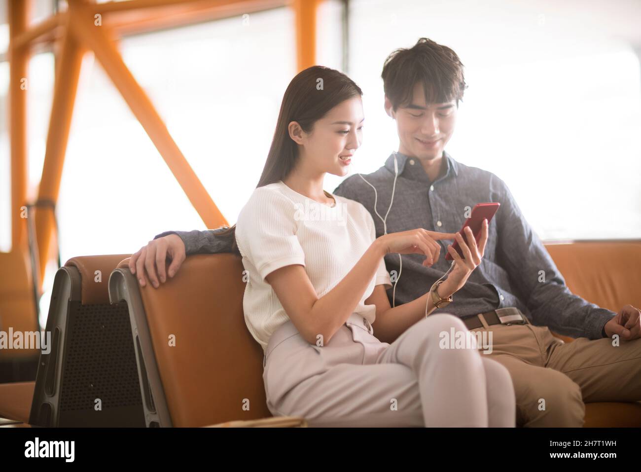 Young couple using mobile phones in airport lounges Stock Photo - Alamy