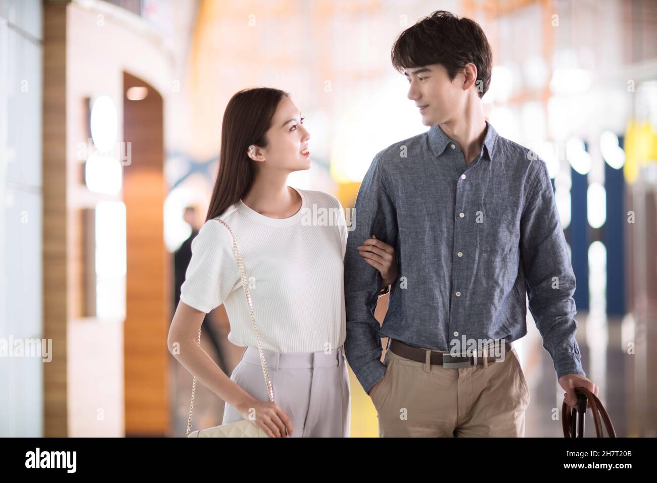 Young lovers lugging suitcases at the airport Stock Photo - Alamy