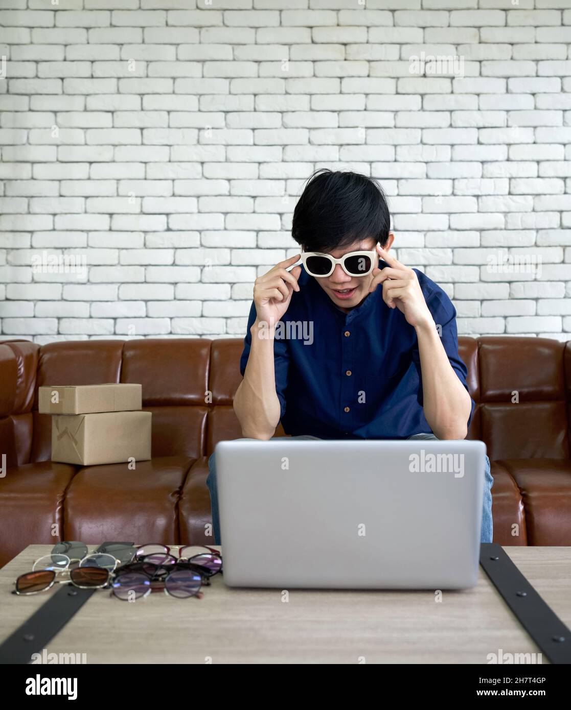 Young man wearing sunglasses facing to computer screen. Asian man sell ...