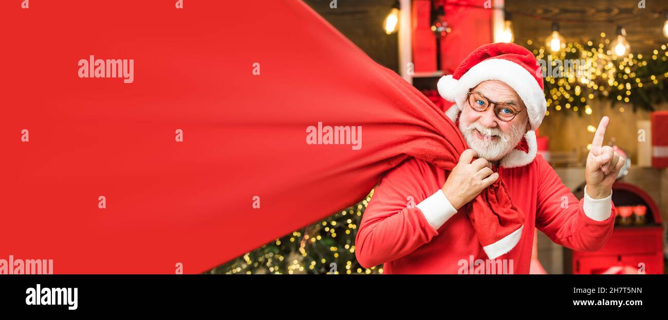 Portrait of handsome Santa man indoors with Christmas gift. Horizontal ...