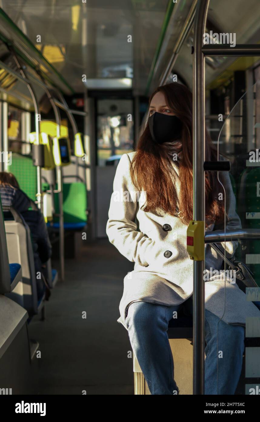 A young woman with a respiratory mask is travelling on public transport ...