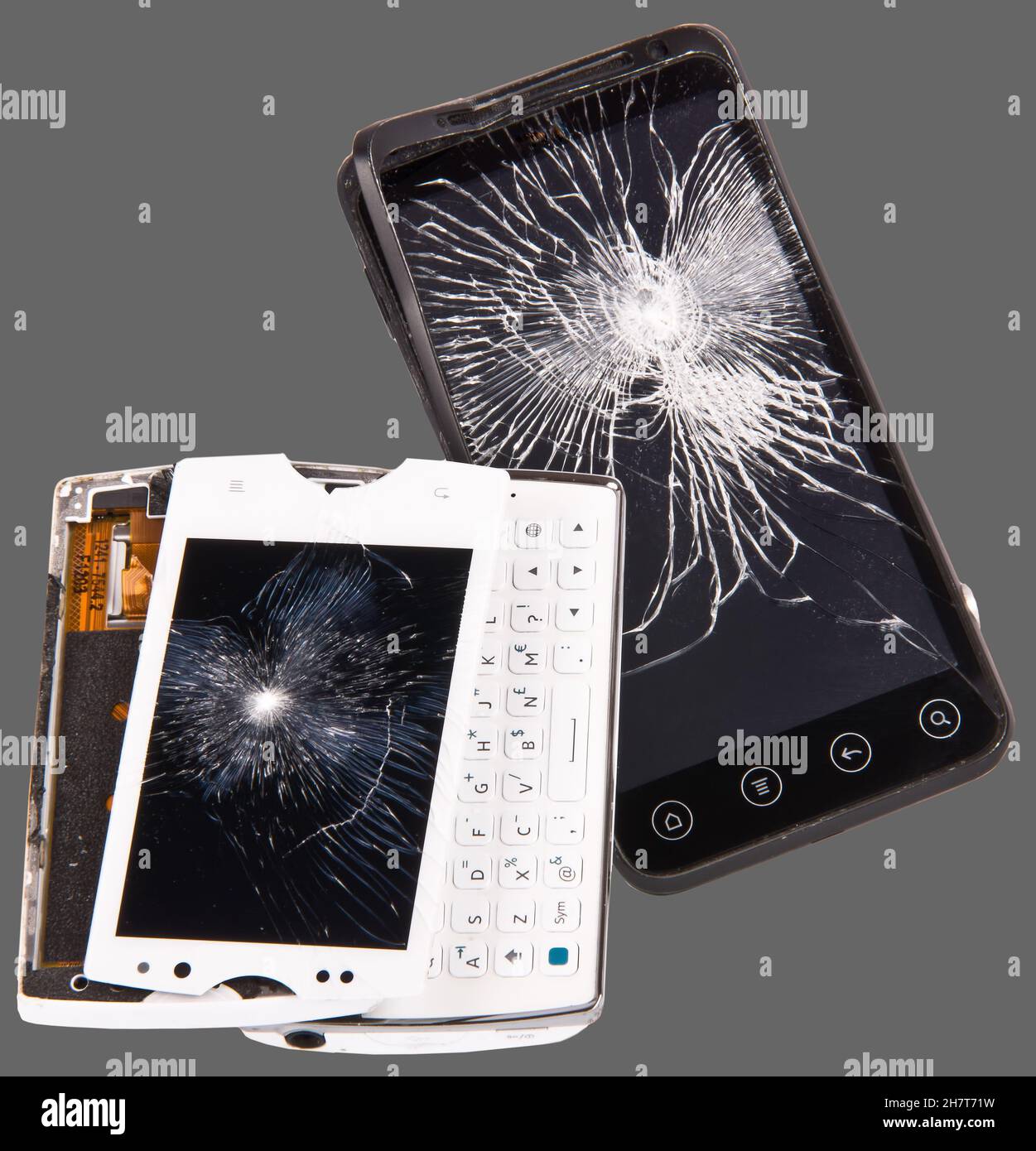 Closeup of two black and white cellphones with broken screens, top ...