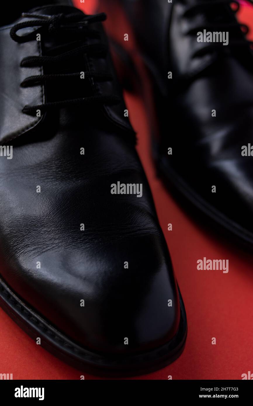 Close-up shot of a classic, black man shoe on the bright red background ...