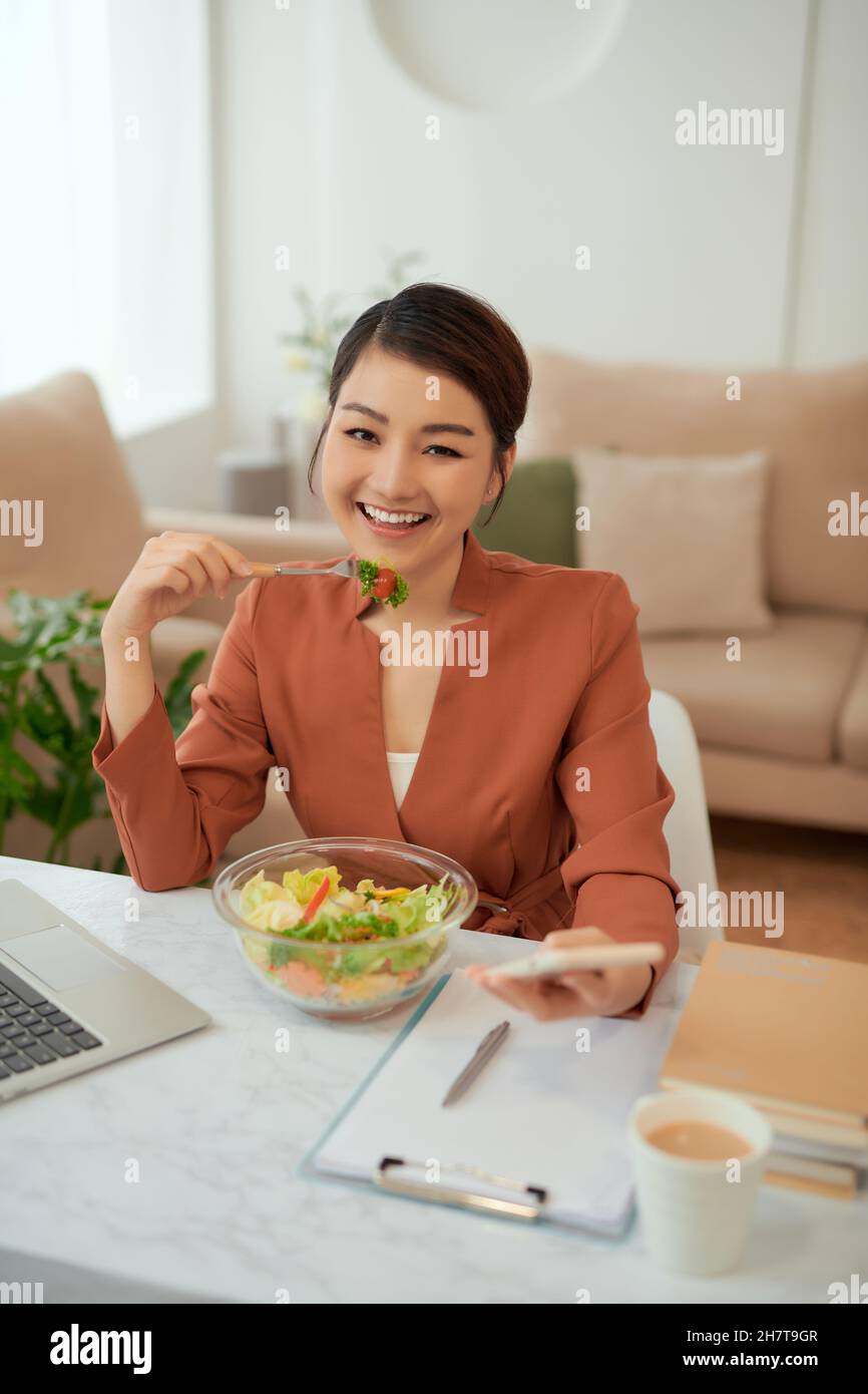 woman with laptop in modern office interior, eating lunch Stock Photo ...