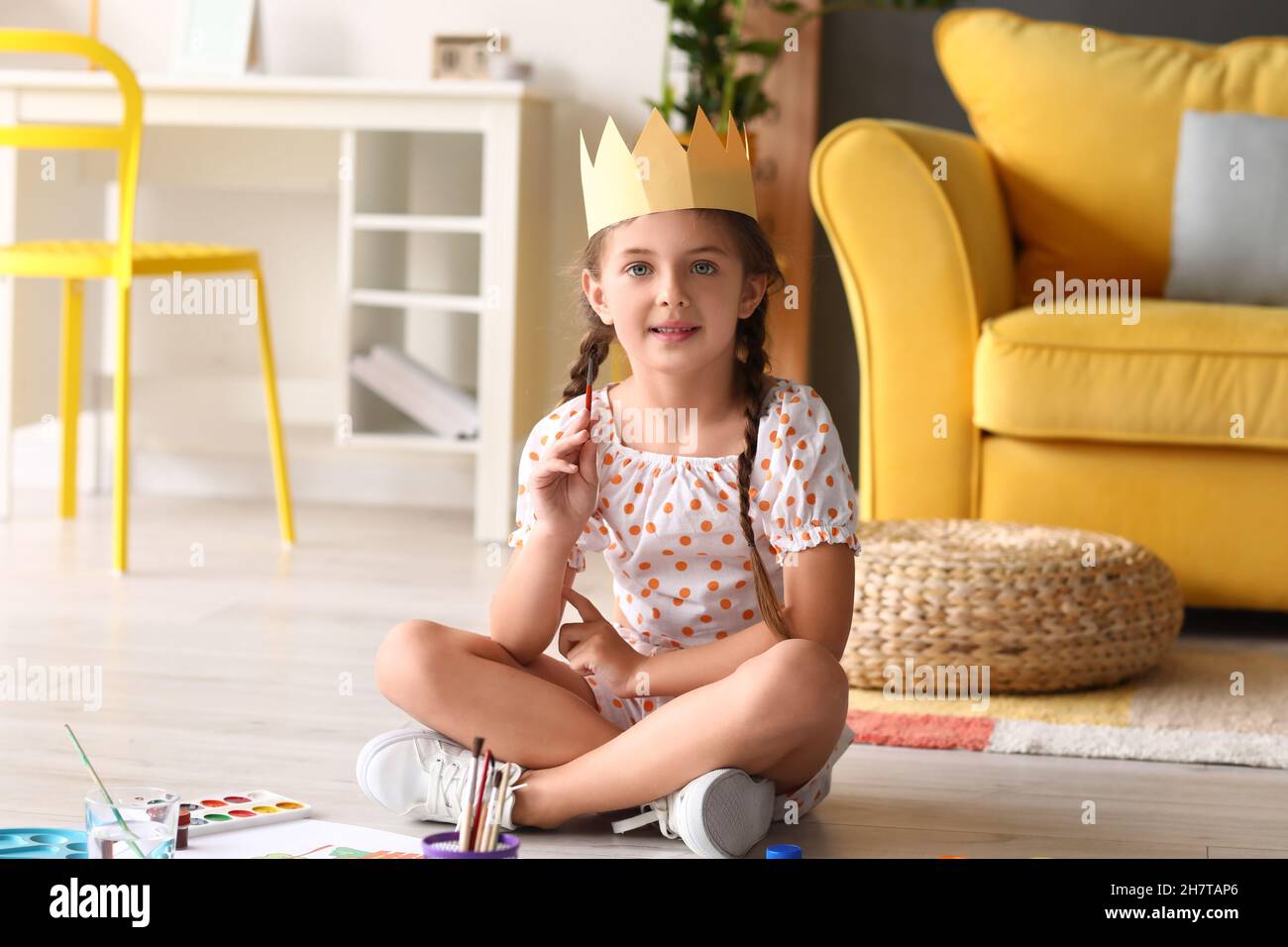 Cute little girl in paper crown painting on floor at home Stock Photo ...