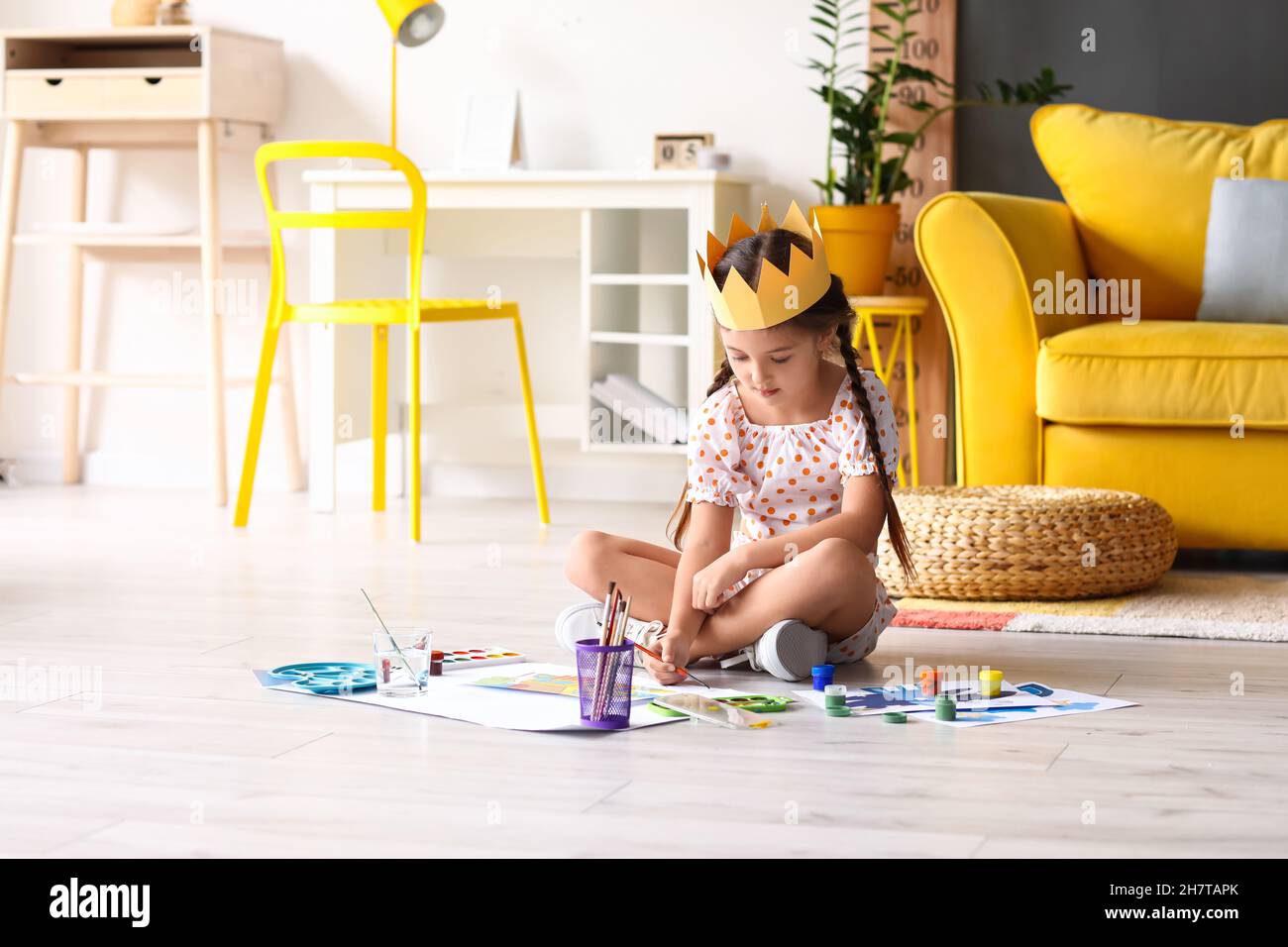 Cute little girl in paper crown painting on floor at home Stock Photo ...