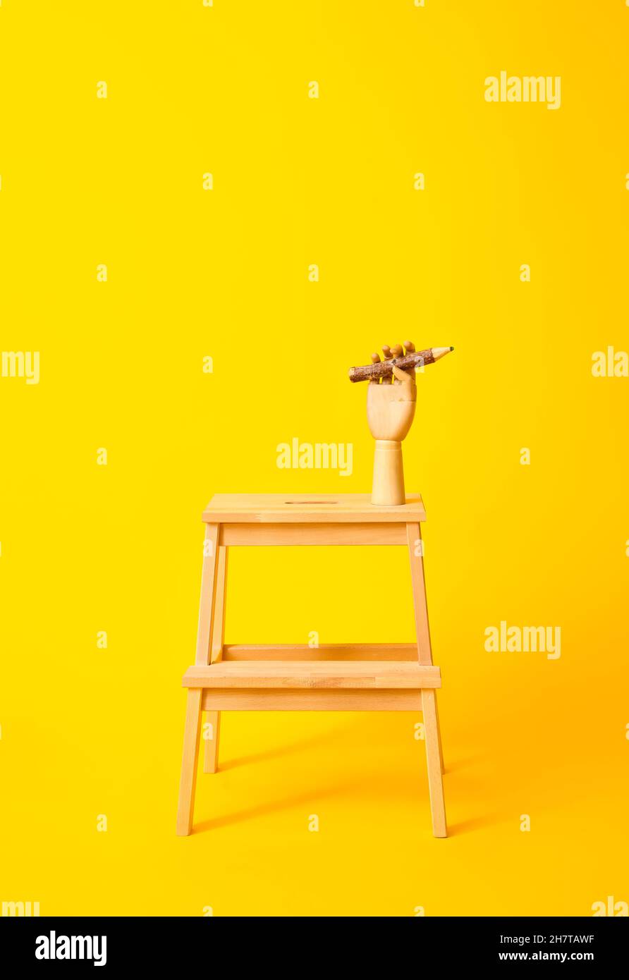 Step stool with wooden hand and pencil on yellow background Stock Photo ...