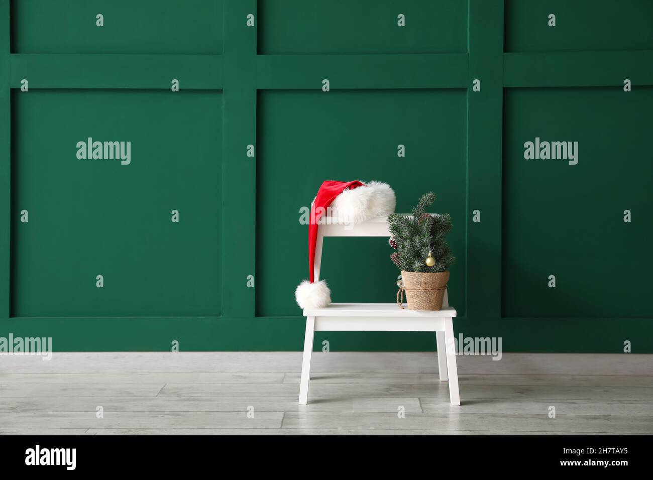 White step stool with Santa hat and small Christmas tree near green ...