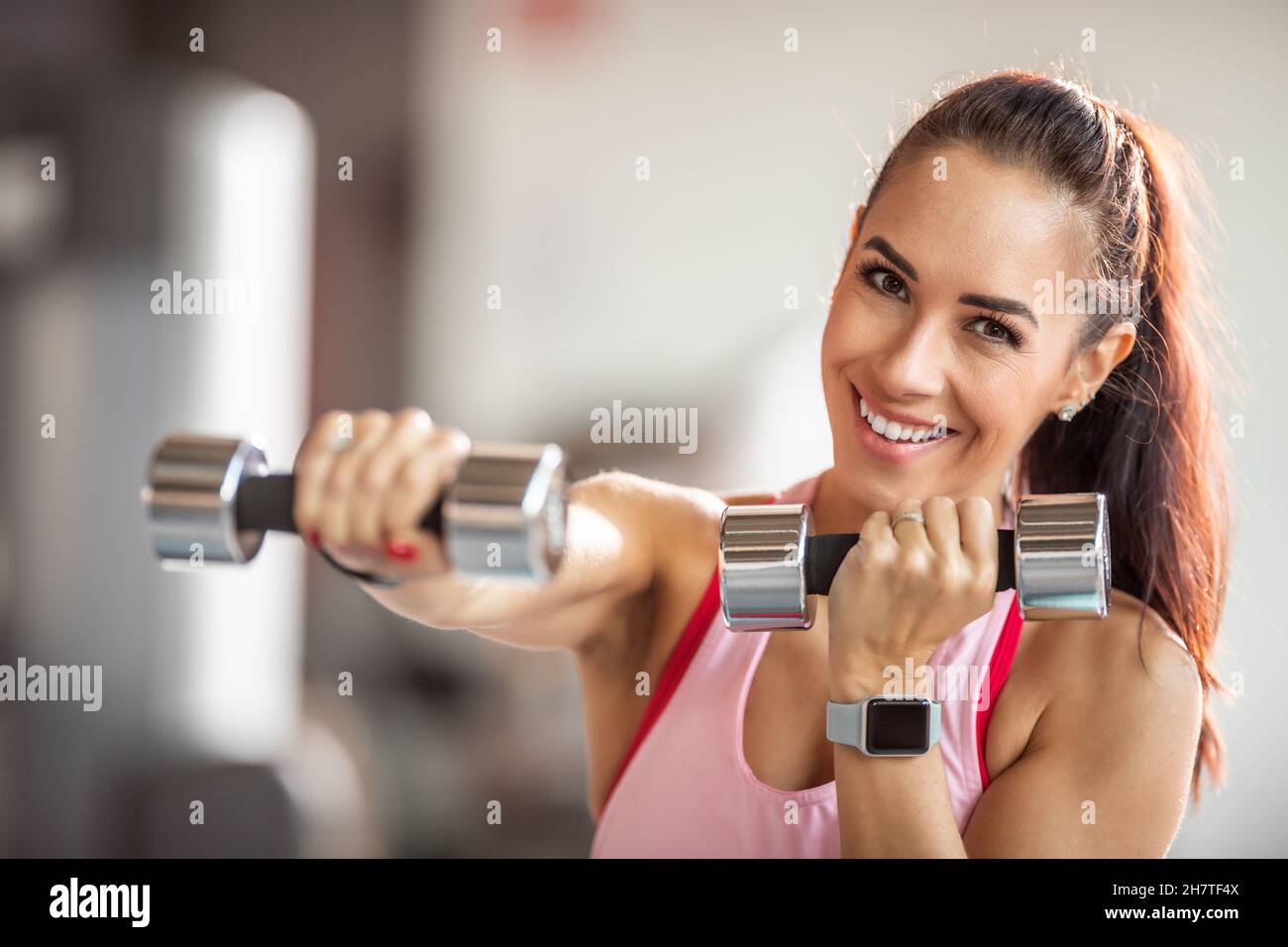 Cute woman smiles at the camera working out with dumbbells Stock Photo ...