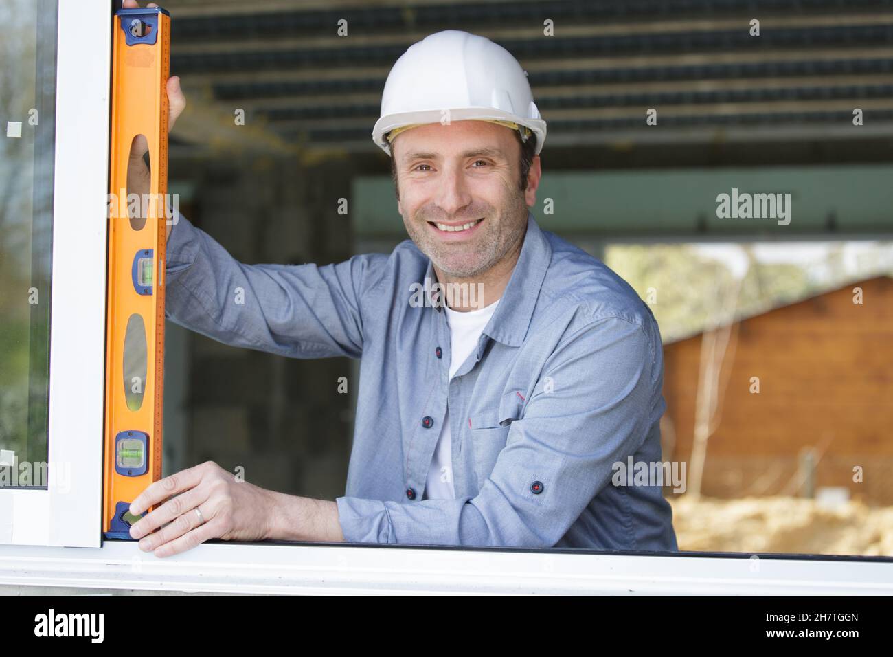 portrait of cheerful and concentrated builder using level Stock Photo ...