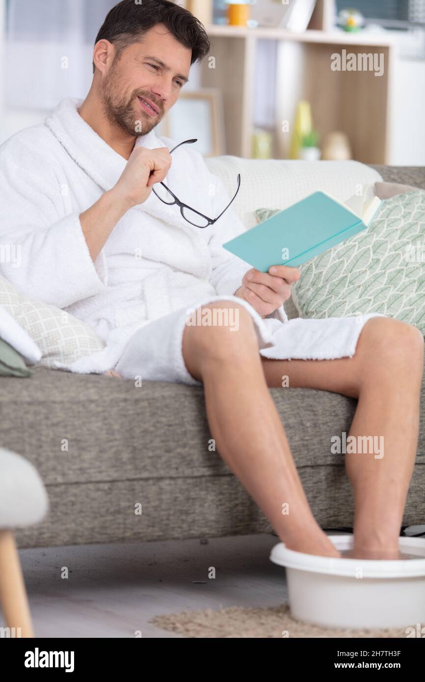 young man reading a book while having a feet bath Stock Photo - Alamy