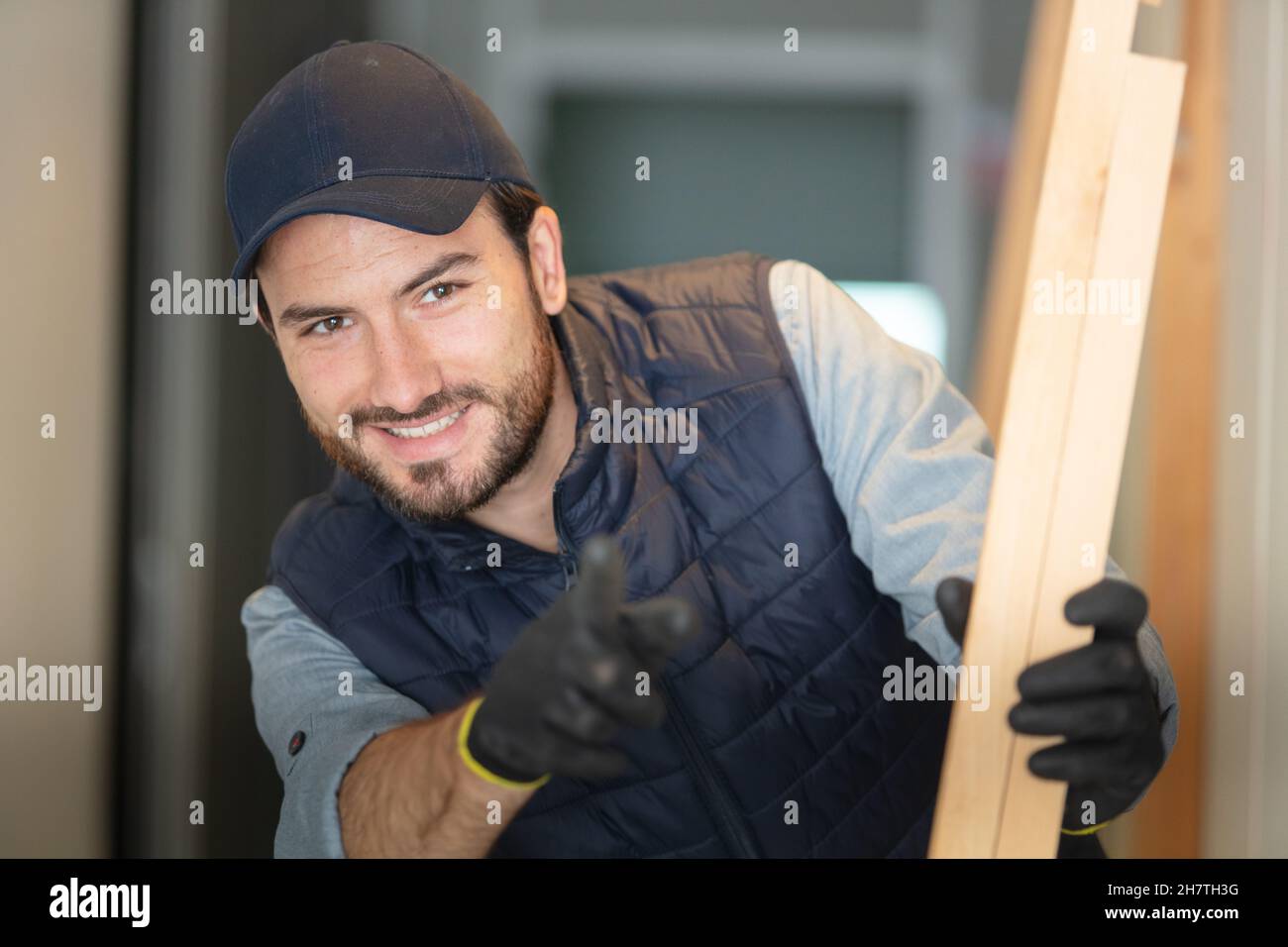 smiling carpenter holding wood planks at a construction site Stock ...