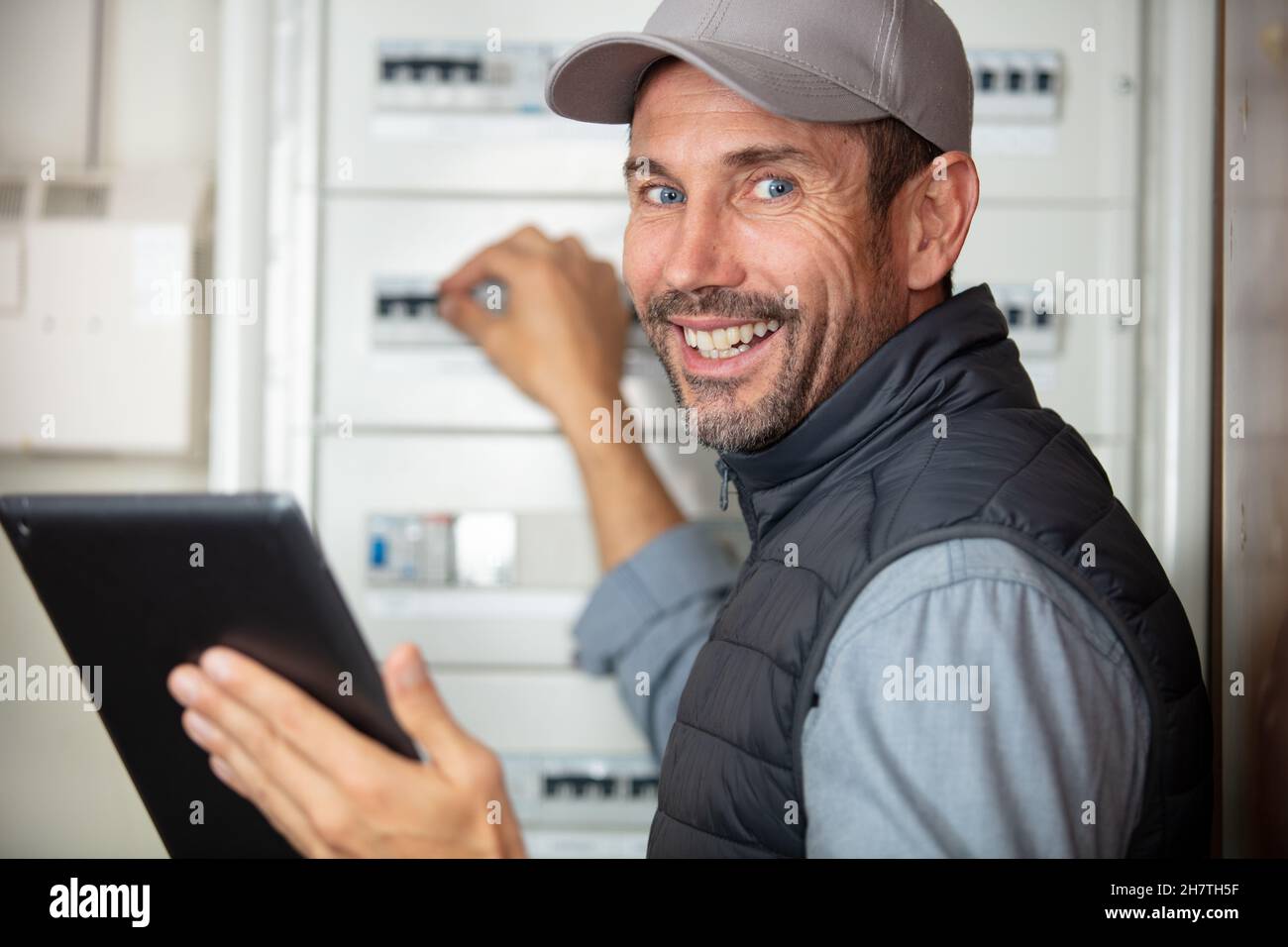 electrician smiling near switch box with tablet computor Stock Photo ...