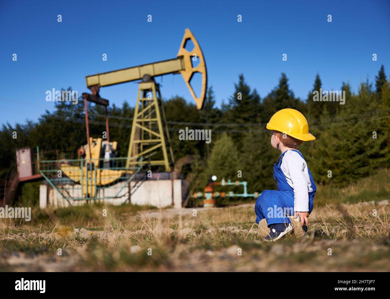 Side view of boy in blue uniform and yellow helmet looking at offshore ...