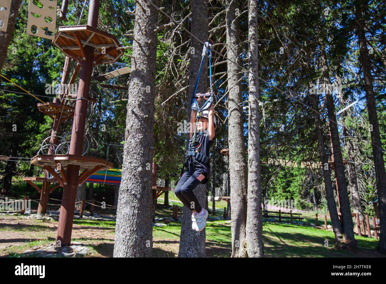 Little girl in safety equipment at adventure amusement park. Child ...