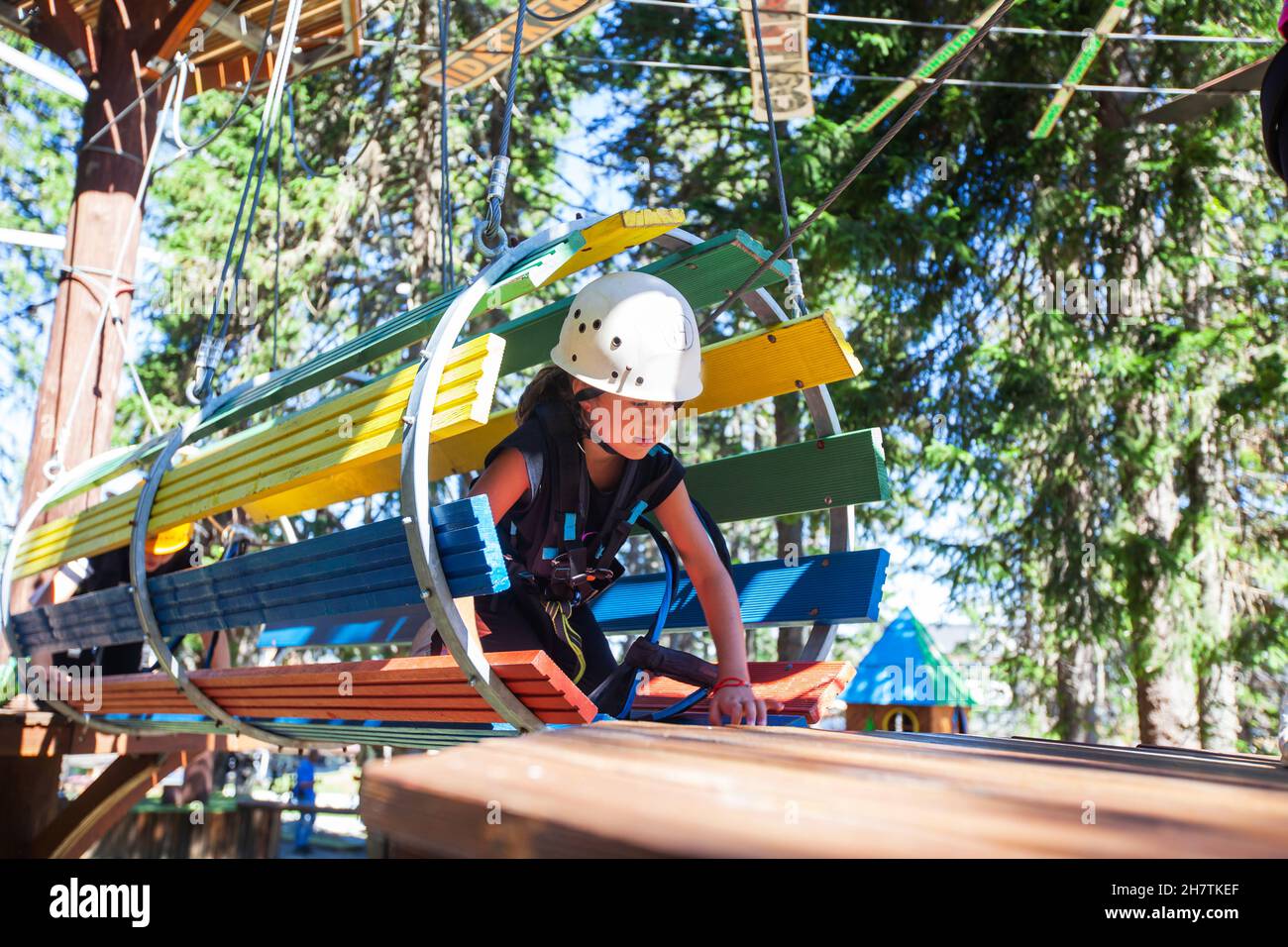 Little girl in safety equipment at adventure amusement park. Child ...