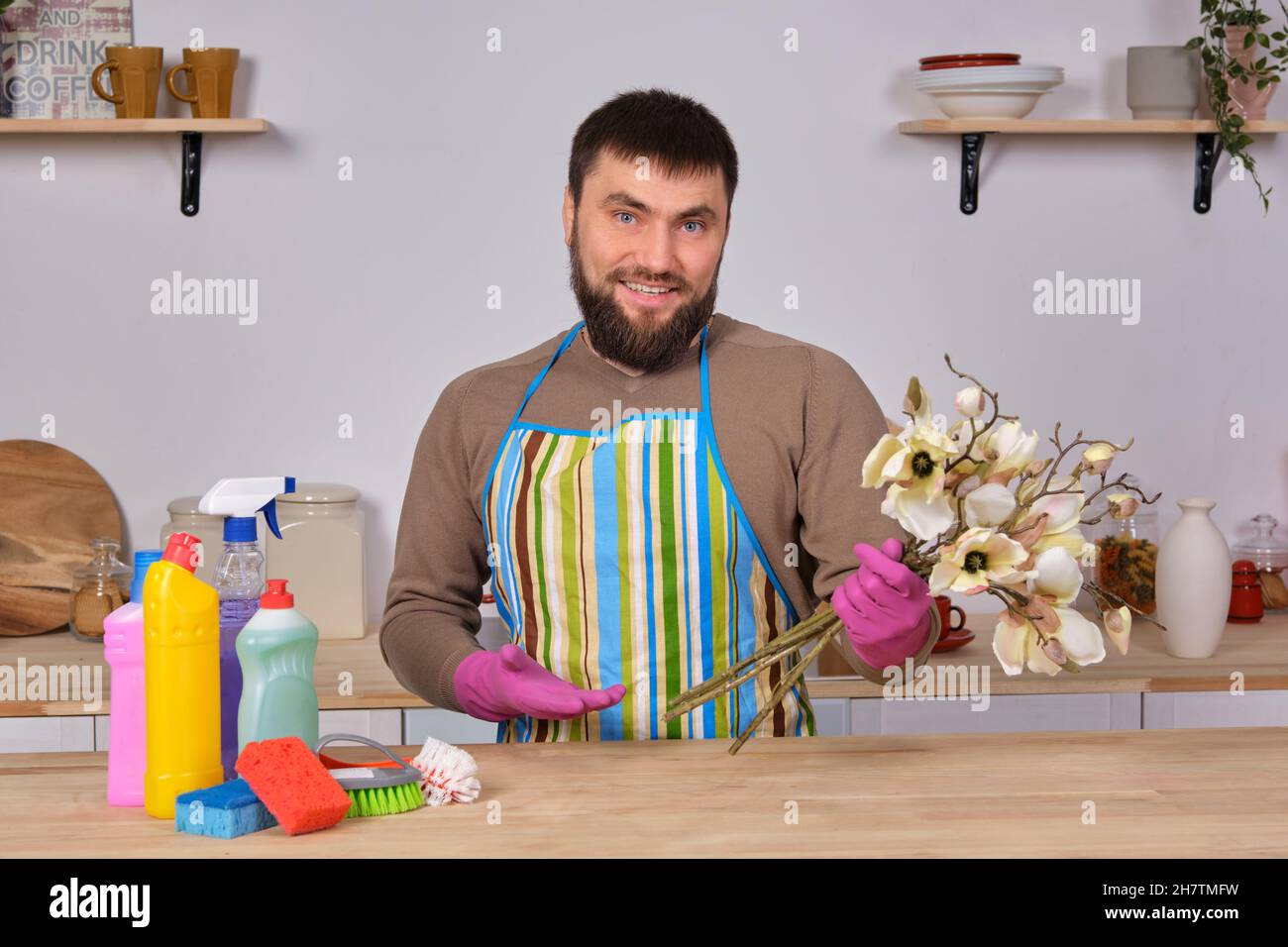 Young handsome bearded man in the kitchen, shows all his cleaning staff ...