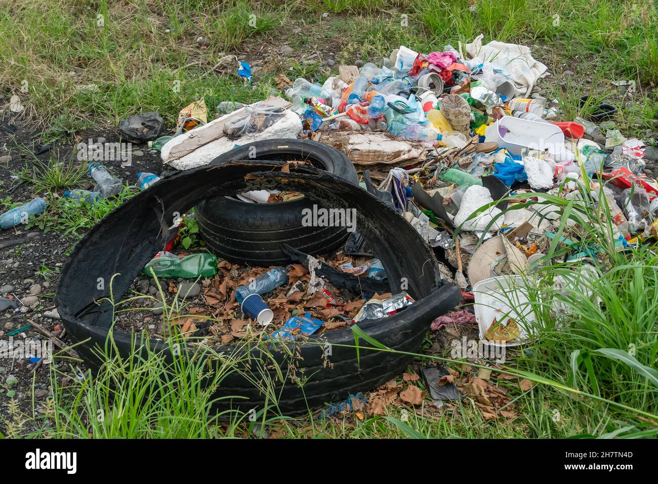 Pile of garbage, plastic, car rubber on the grass in close-up. Concept ...