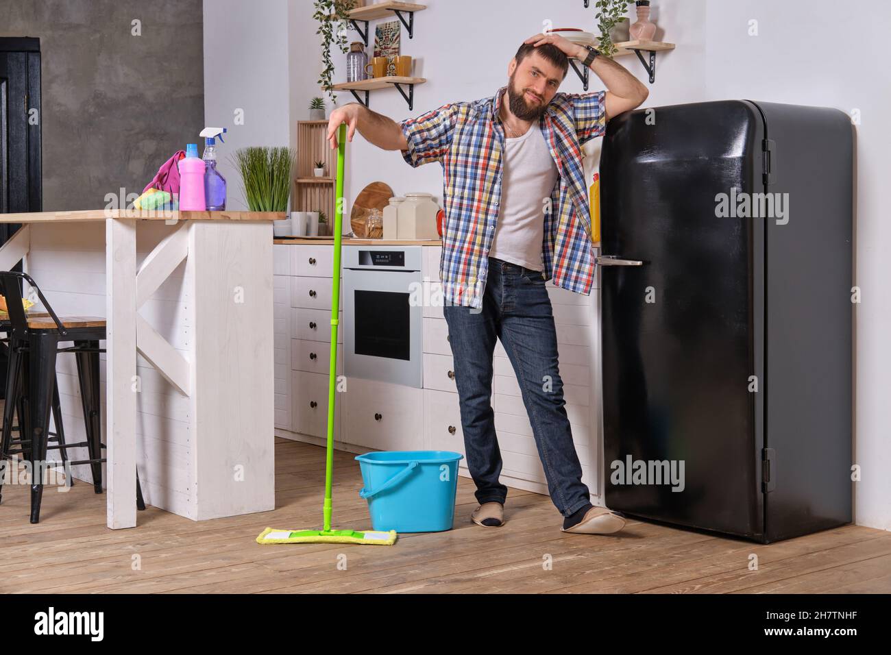 Husband housekeeper cleans the kitchen. Young happy man with green mop ...