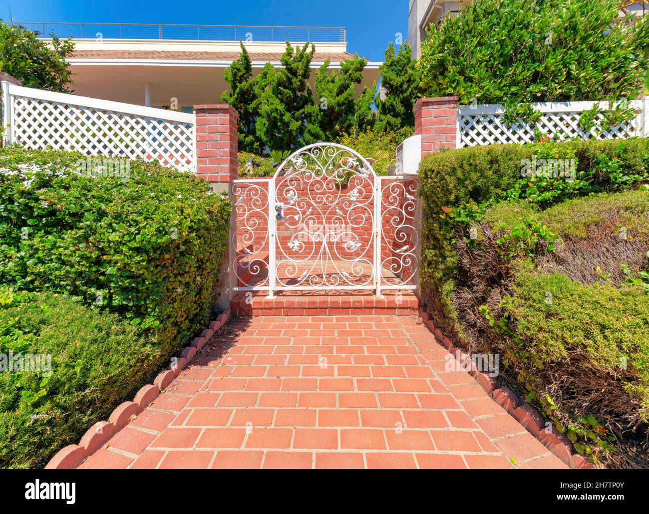 White wrought iron gate of a house with red bricks entrance and walls ...