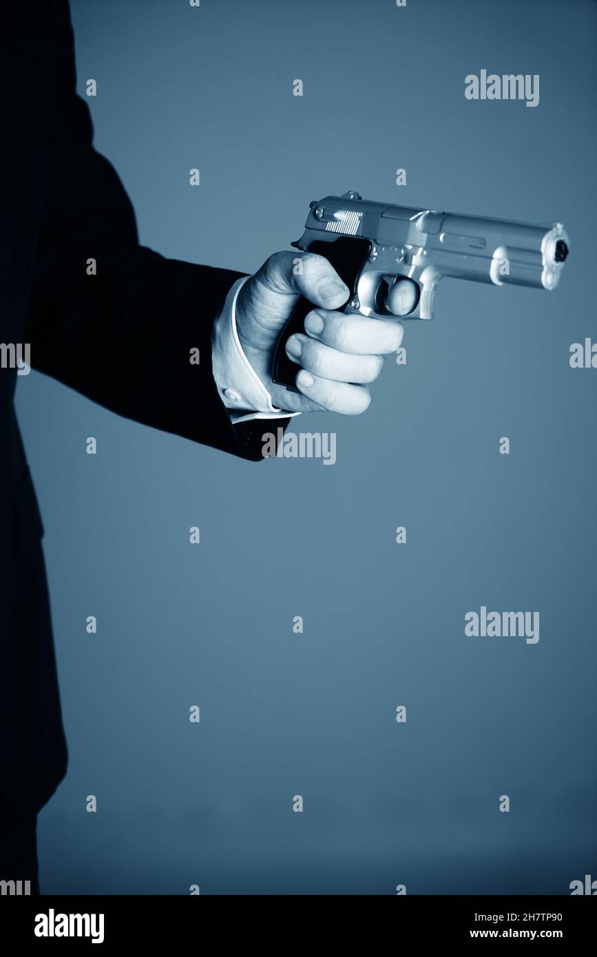 Retro secret agent with pistol revolver gun in hand in vintage crime ...