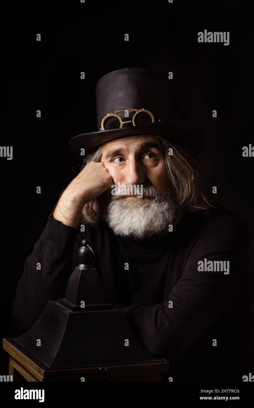A gray-haired bearded intellectual of mature age in a steampunk hat ...