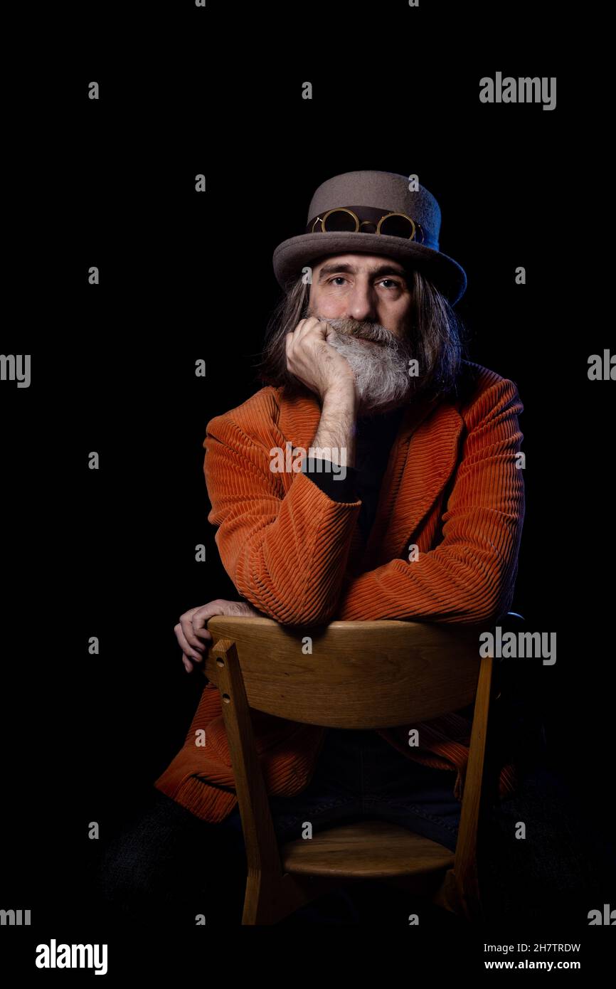 A mature gray-haired bearded intellectual wearing a steampunk hat and ...