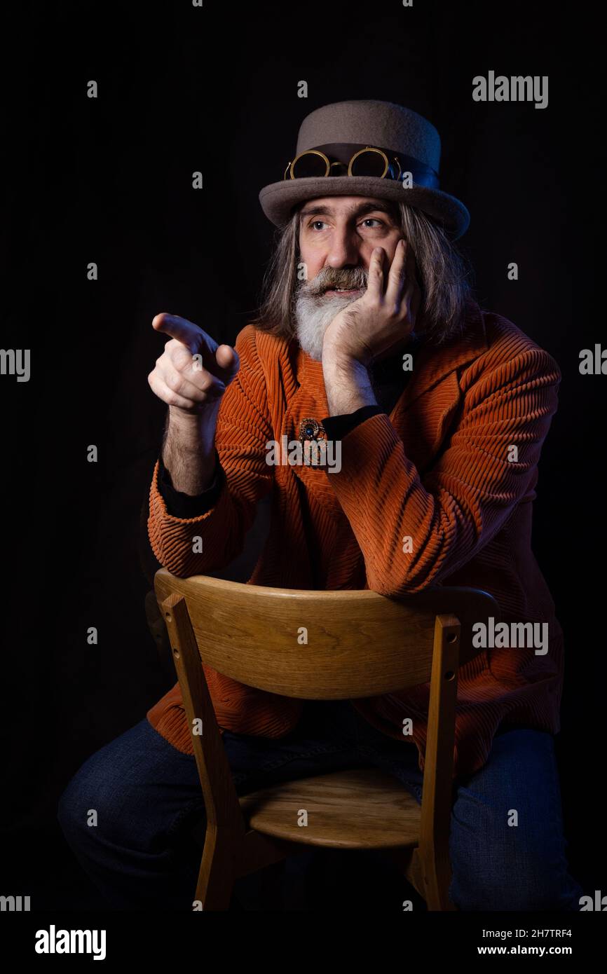 A gray-haired bearded intellectual of mature age in a steampunk hat and ...