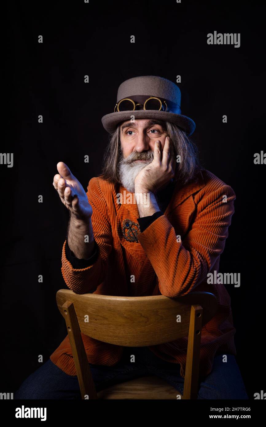 A gray-haired bearded intellectual of mature age in a steampunk hat and ...
