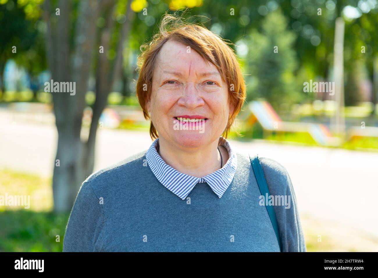 Smiling mature lady in urban park Stock Photo - Alamy