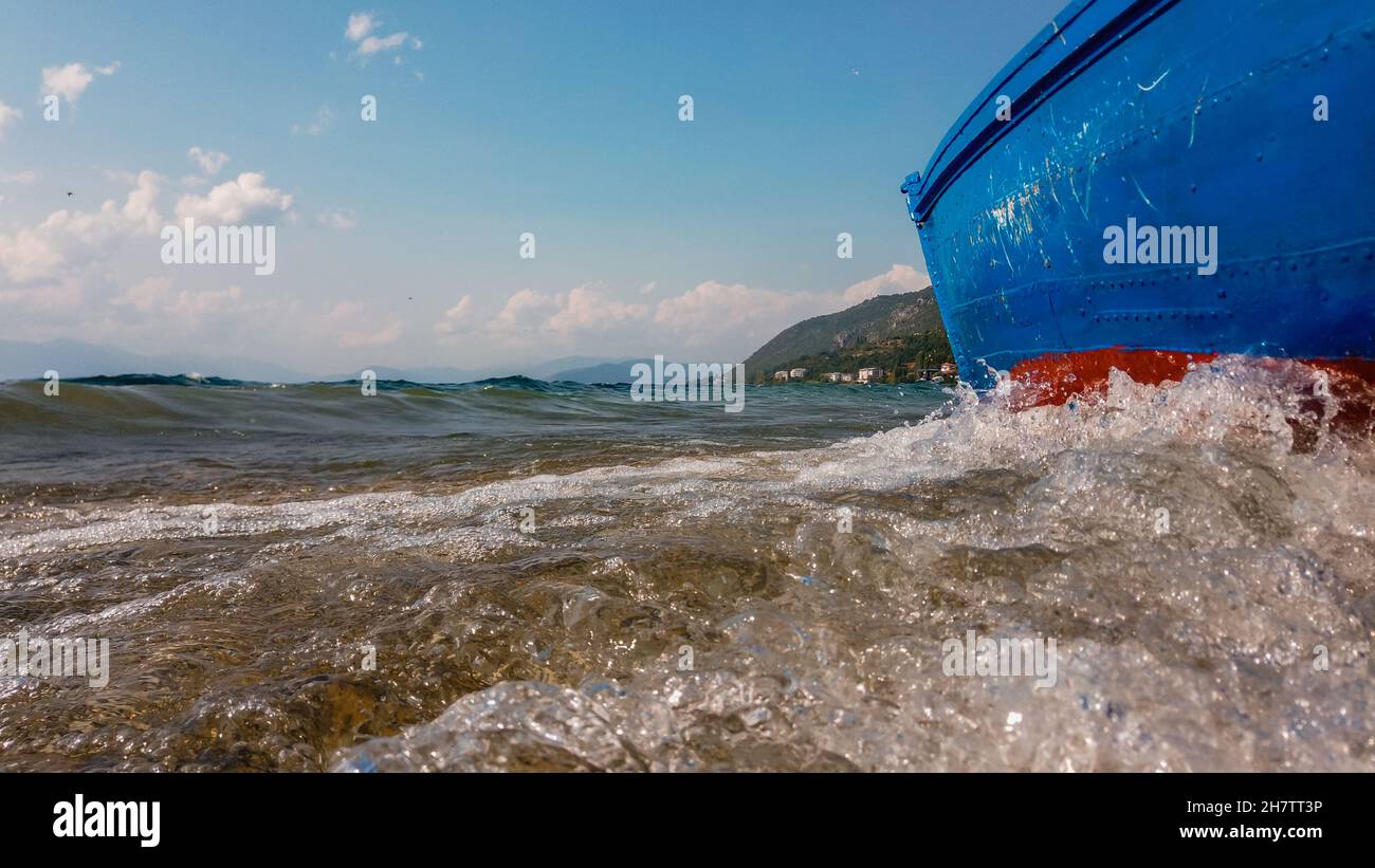 Waves hit the blue boat on the lake shore, underwater Stock Photo - Alamy