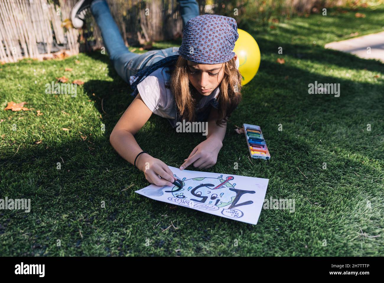 Teenage girl activist painting a protest sign in the garden on a spring ...