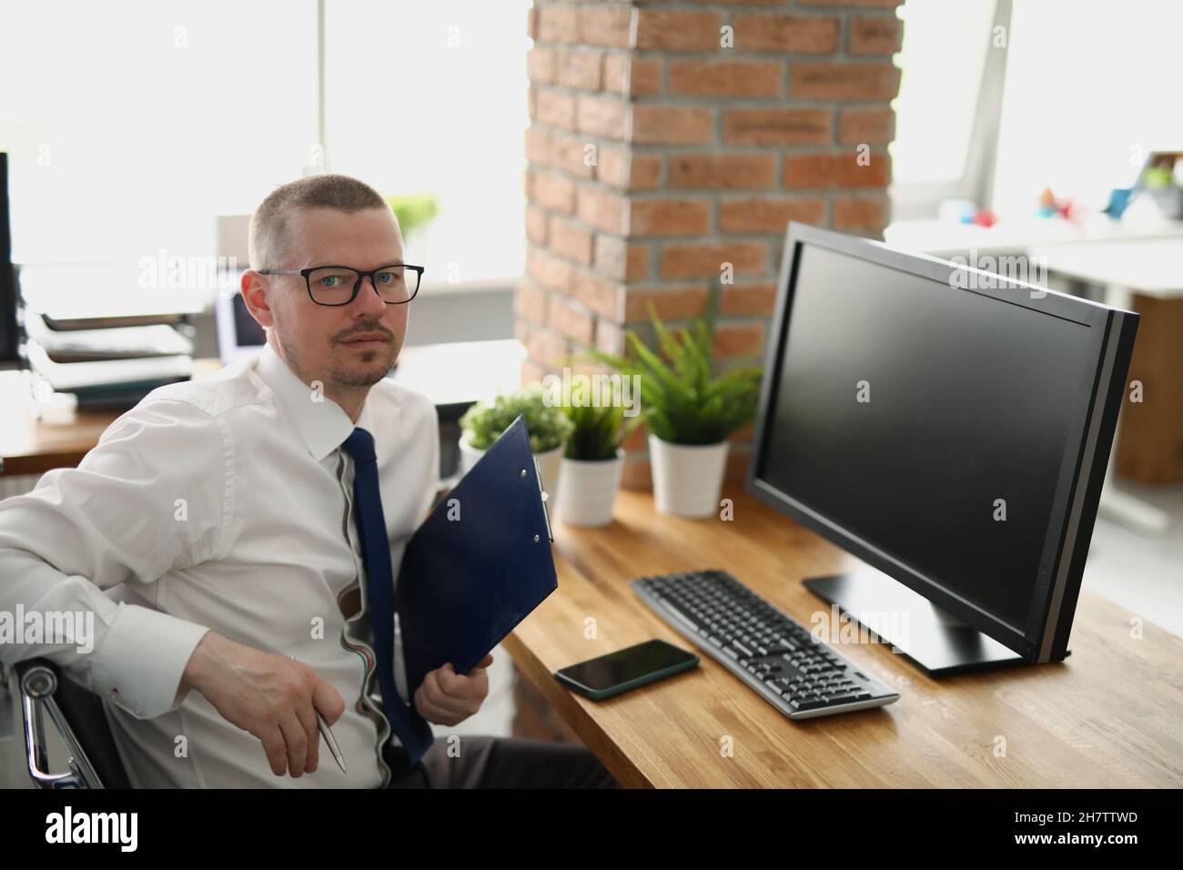 Business office worker sitting on workplace with clipboard Stock Photo ...