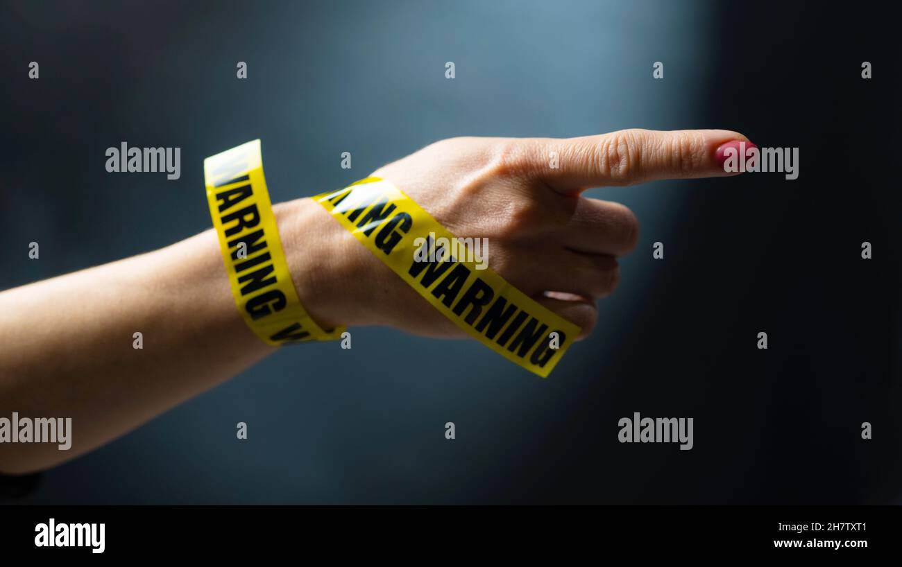 Hand with warning tape shows signs Stock Photo - Alamy
