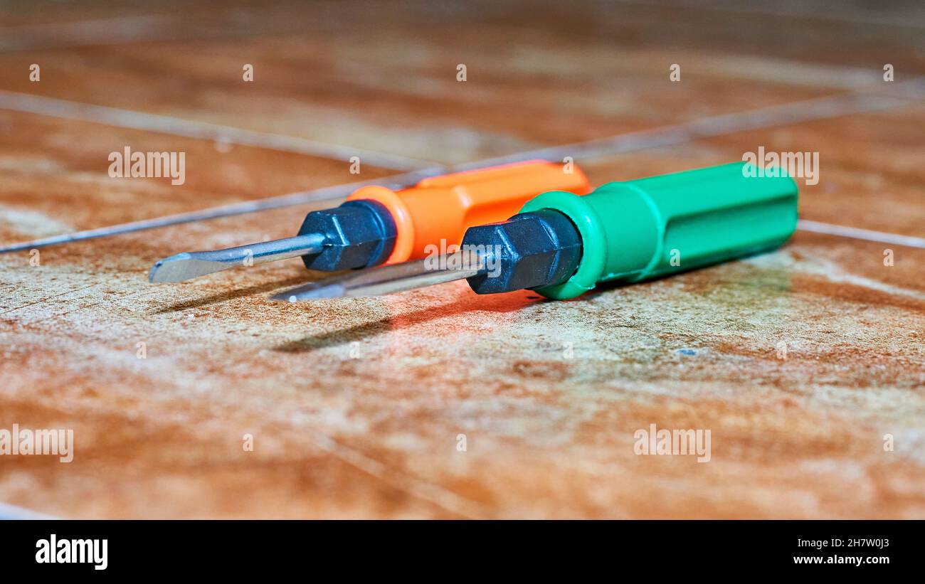 Green and orange screwdrivers on brown marble tiles Stock Photo - Alamy