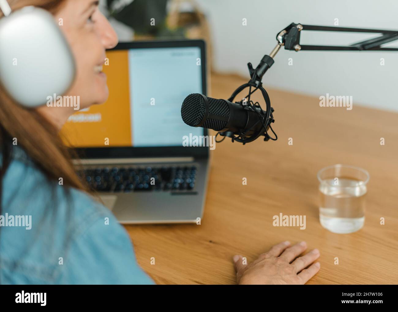 Woman recording podcast at table with mic Stock Photo - Alamy