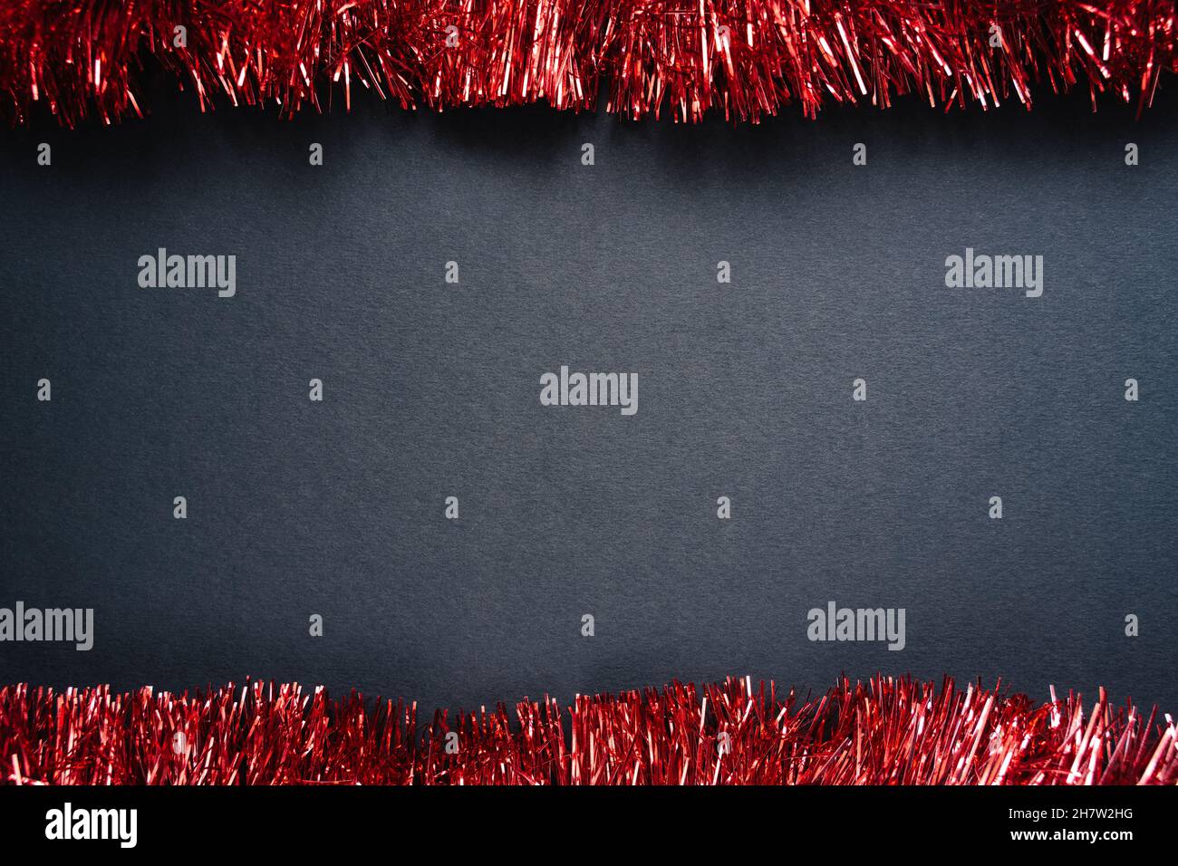red tinsel frame on black paper background. Christmas holiday season ...