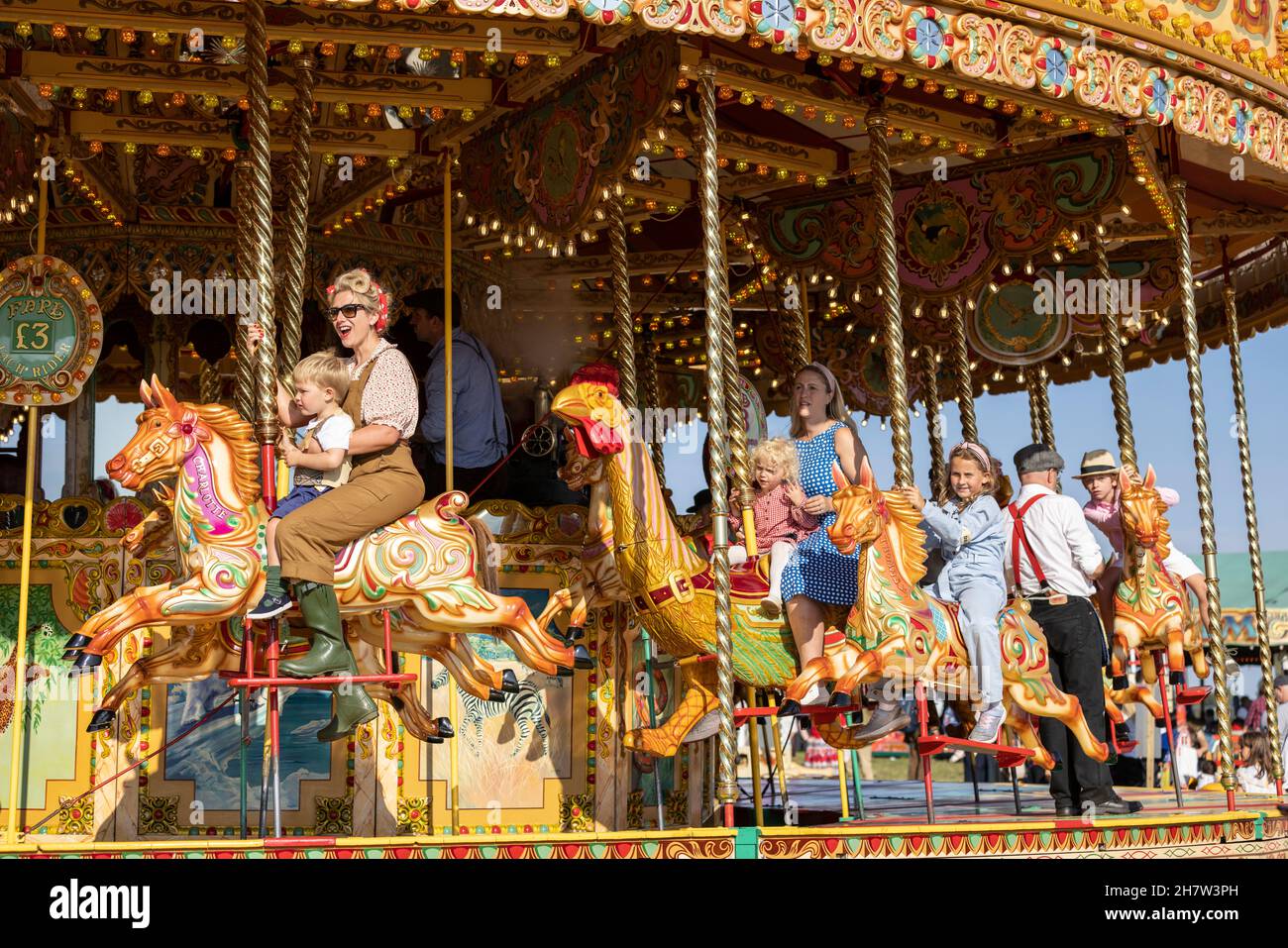 Families enjoy the Carousel funfair ride at Goodwood Revival festival ...