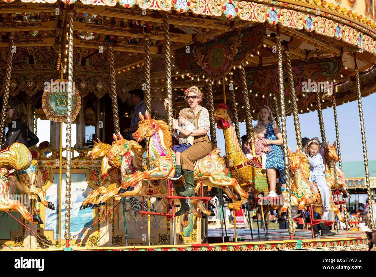Families enjoy the Carousel funfair ride at Goodwood Revival festival ...