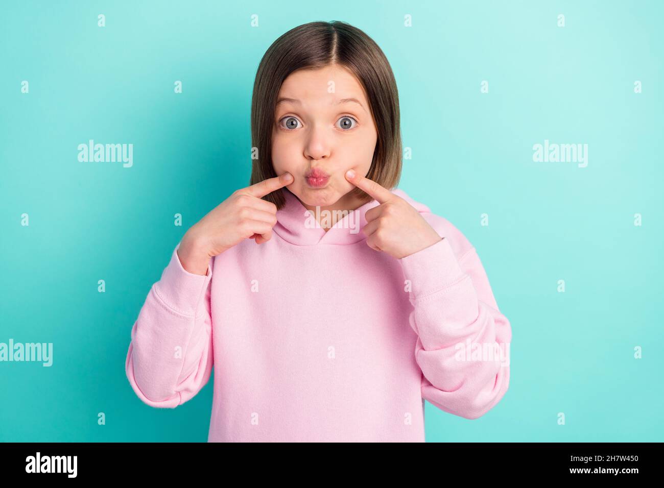 Photo of impressed short hairdo little girl press cheeks wear pink ...