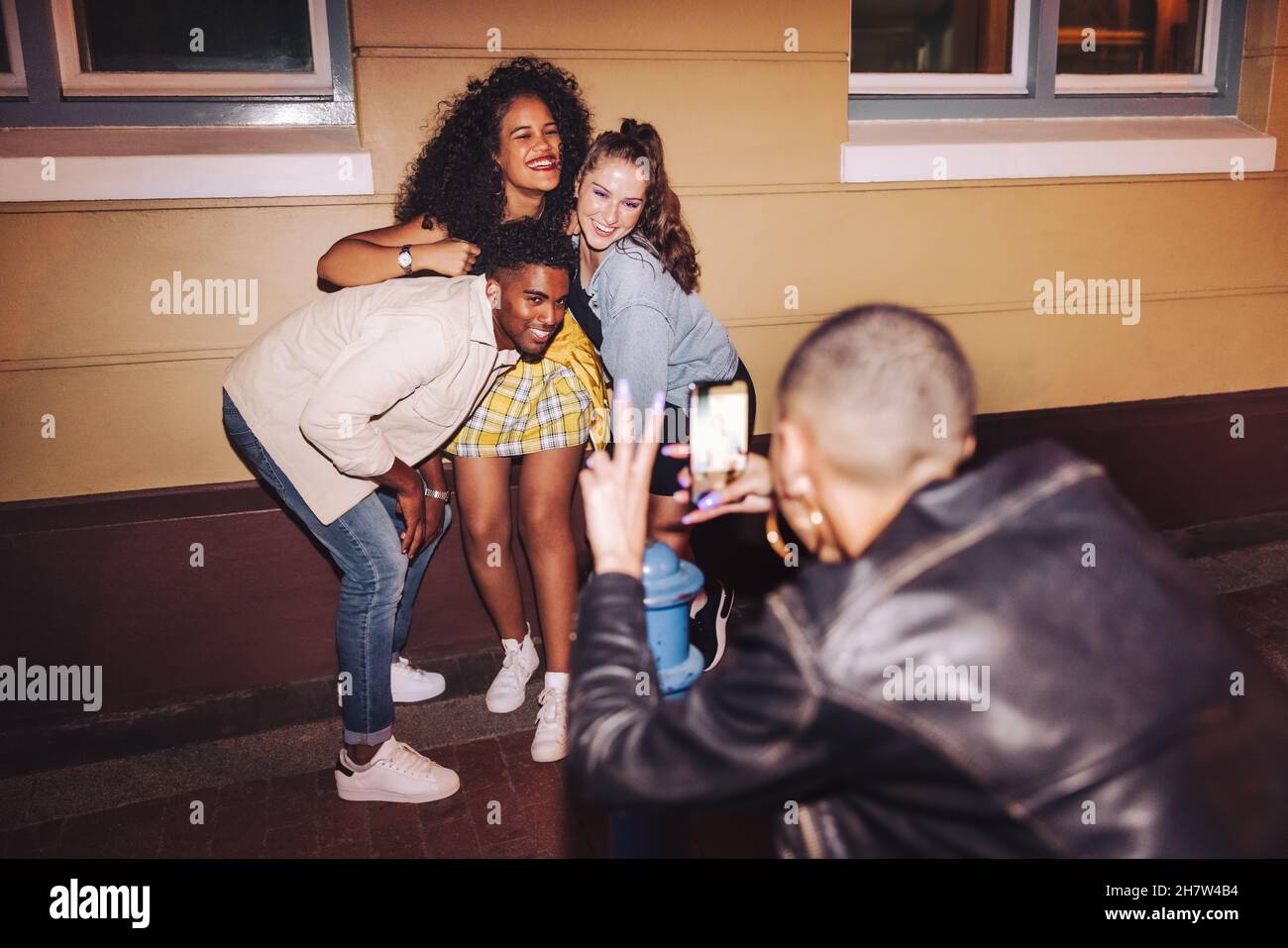 Young friends posing for a photo in front of a camera phone. Group of ...