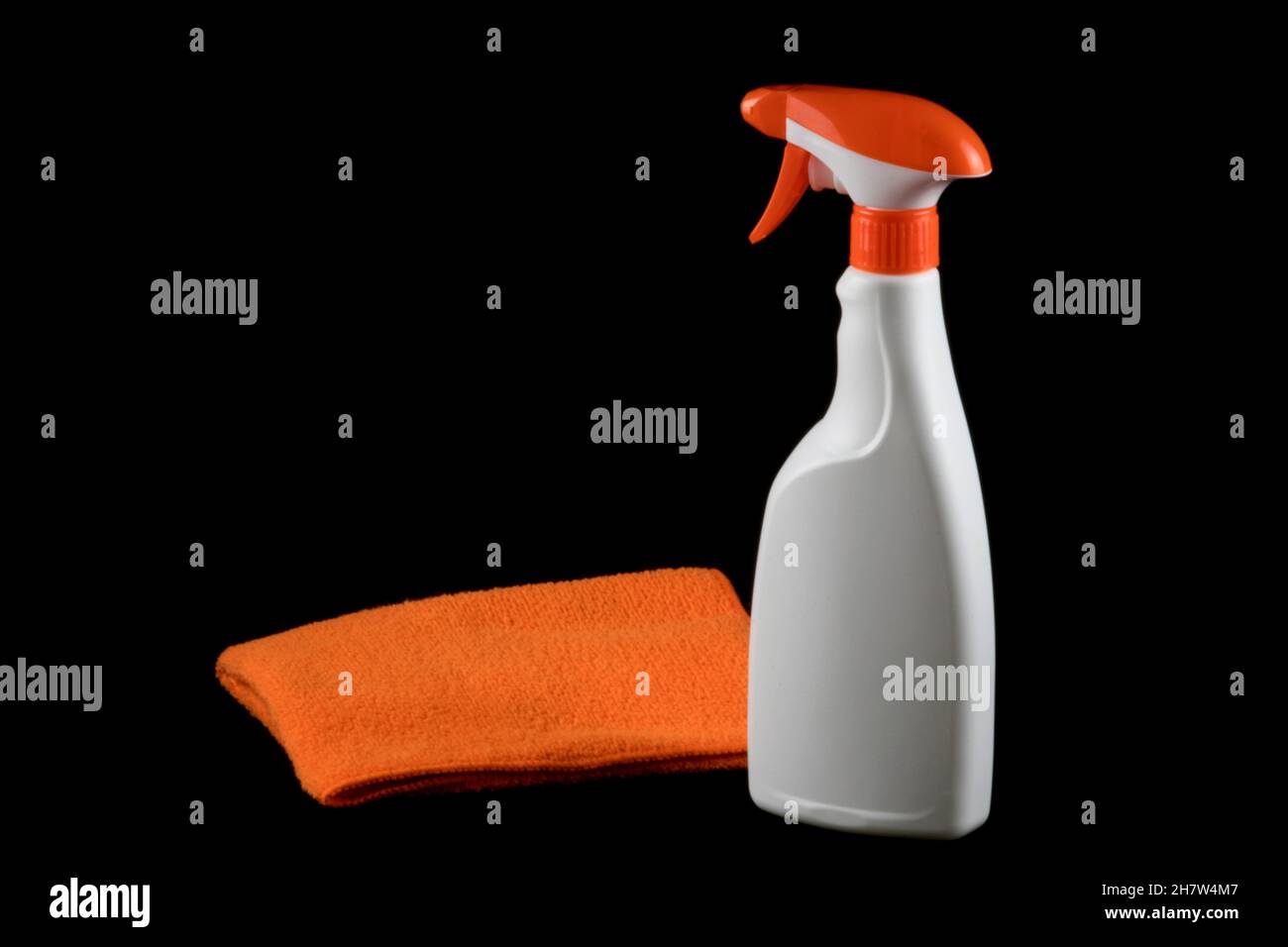 Spray cleaner bottle and yellow cleaning cloth isolated on a black ...
