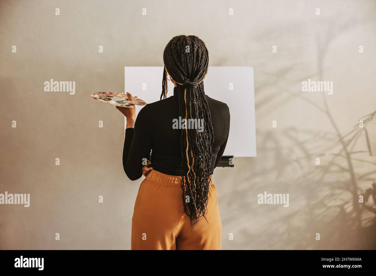 Creative young woman holding a palette while standing in front of a ...