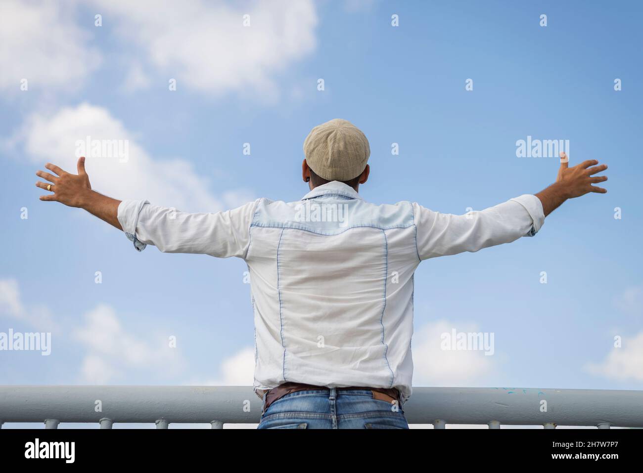 Back view of a man raising his arms up against sky Stock Photo - Alamy